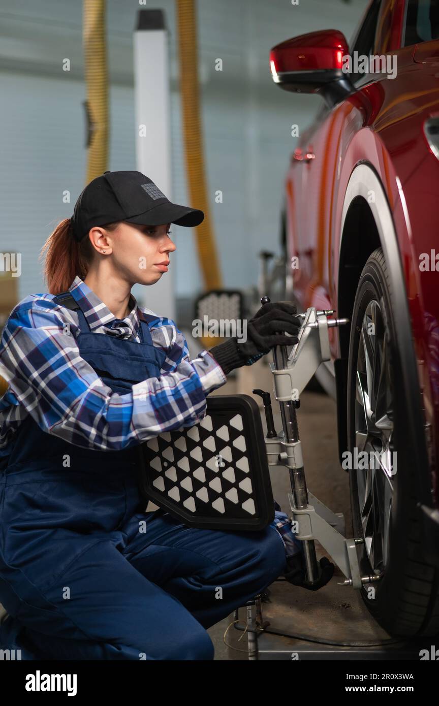 A female auto mechanic makes a camber. Woman working in a car service ...