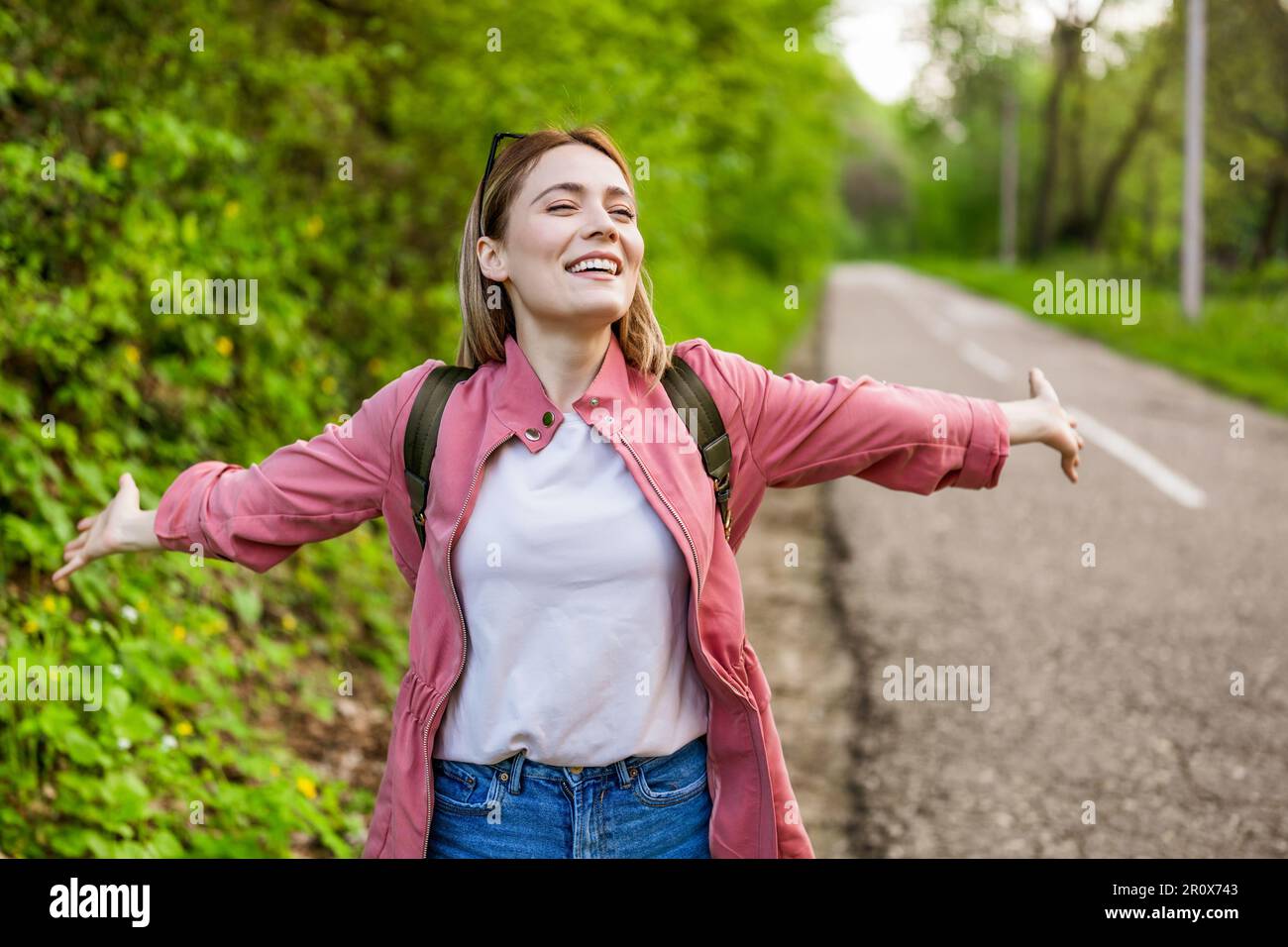 Happy woman is ready for hiking in forest. She is standing beside the ...