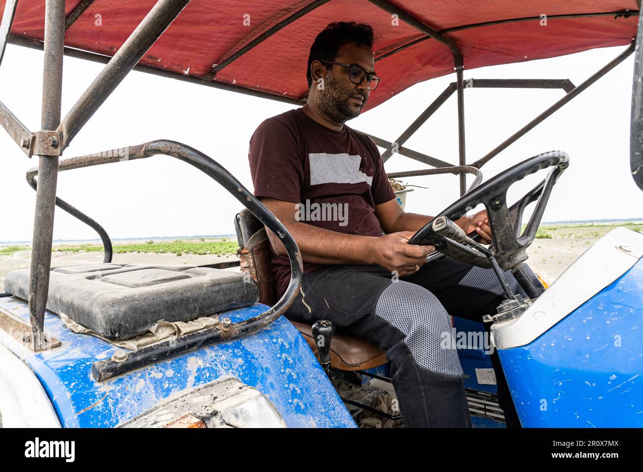 A middle-aged male farmer driving his tractor during harvest in the ...