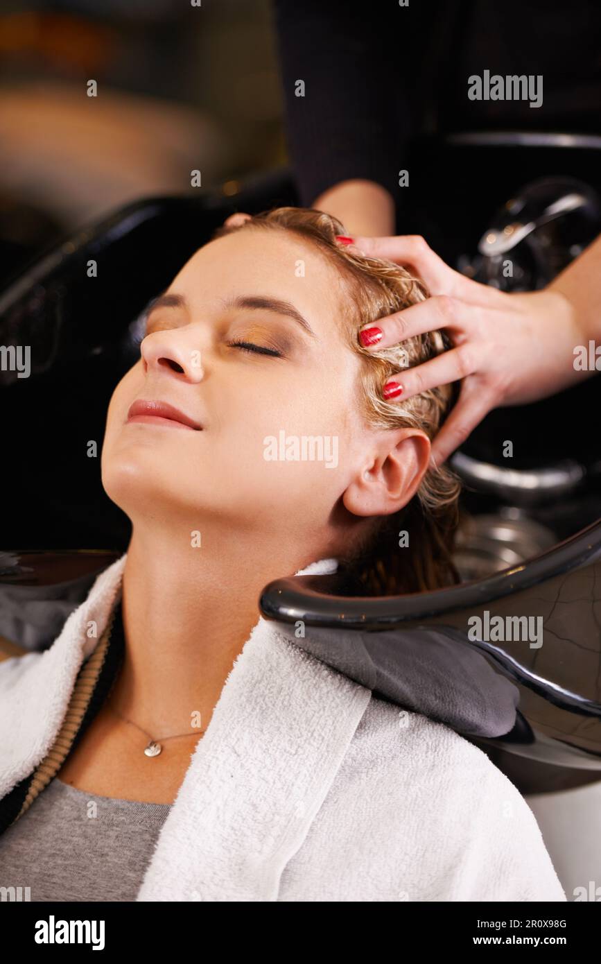 The perks of a visit to the hair salon. a young woman having her hair ...