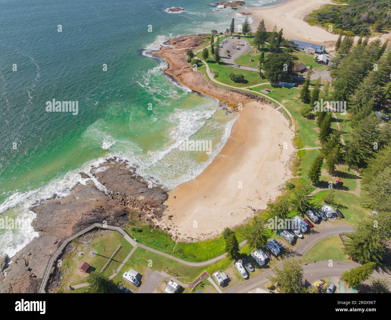 Aerial view of cars parked above a small cove with a sandy beach at ...