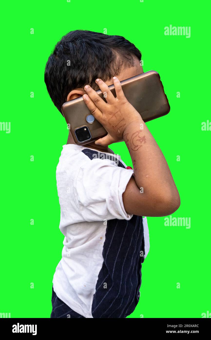 A little boy having a serious smartphone call isolated on the green ...
