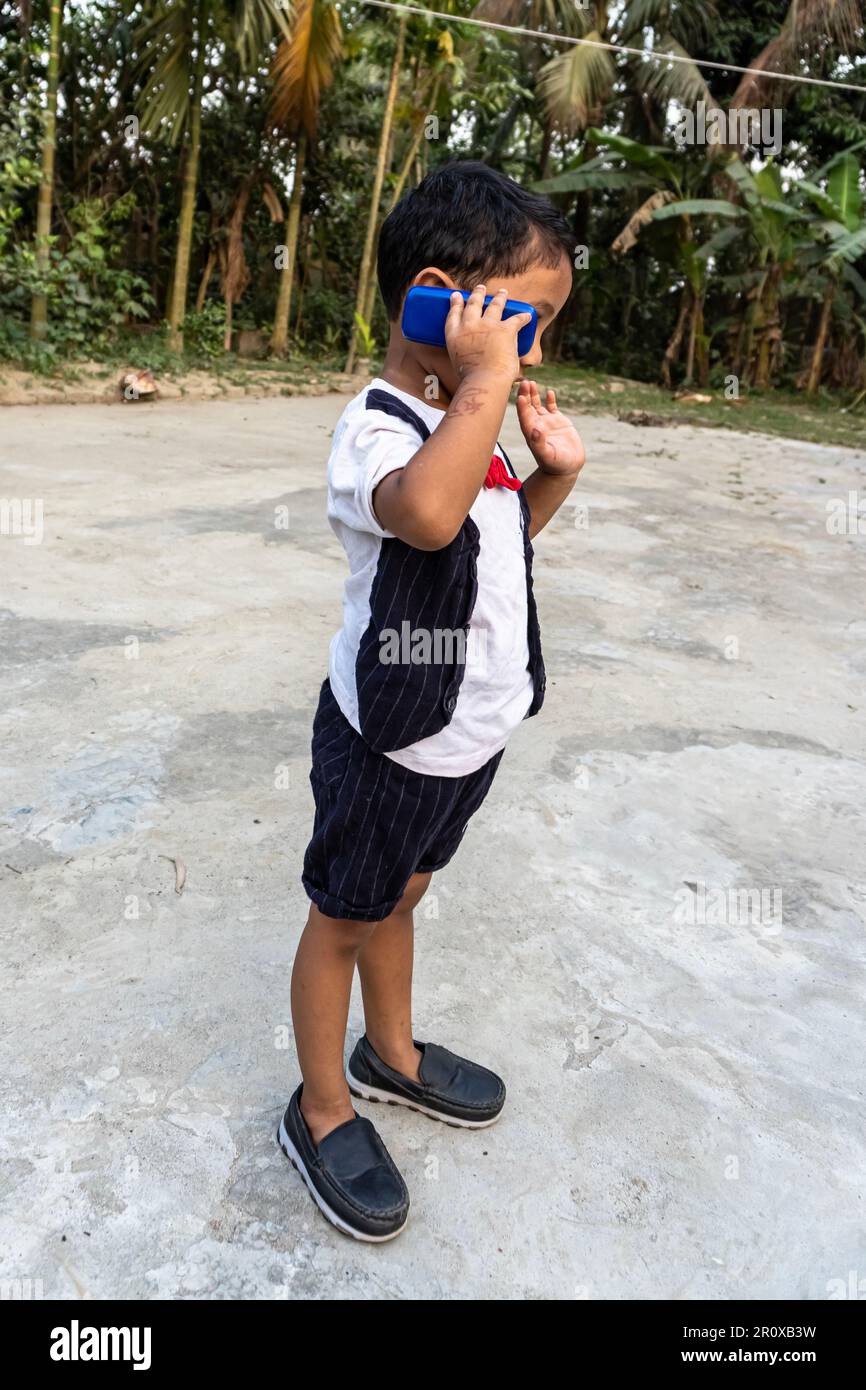 A small boy uses a mobile phone to talk with positive emotions. A young ...
