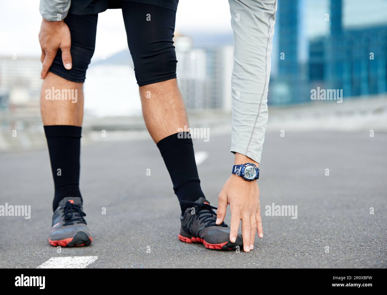 Limbering up for a run. a jogger standing on a road stretching Stock ...