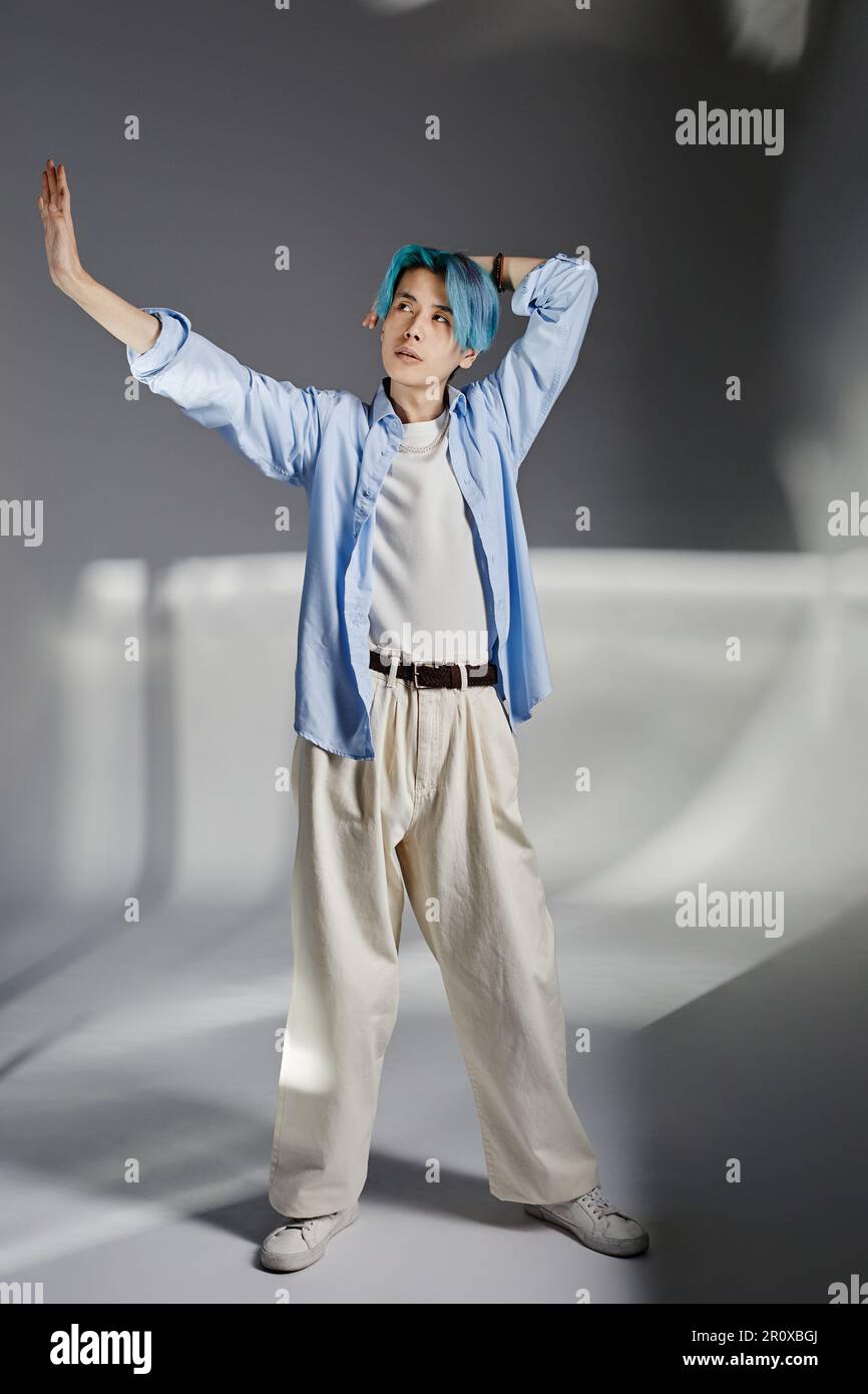 Vertical image of Asian young dancer standing in pose against grey ...