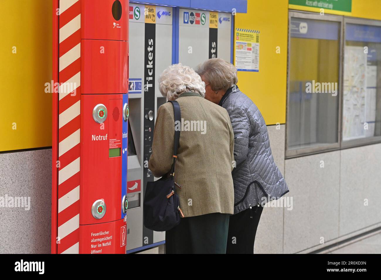 Two seniors, old women are standing in front of a ticket machine from ...
