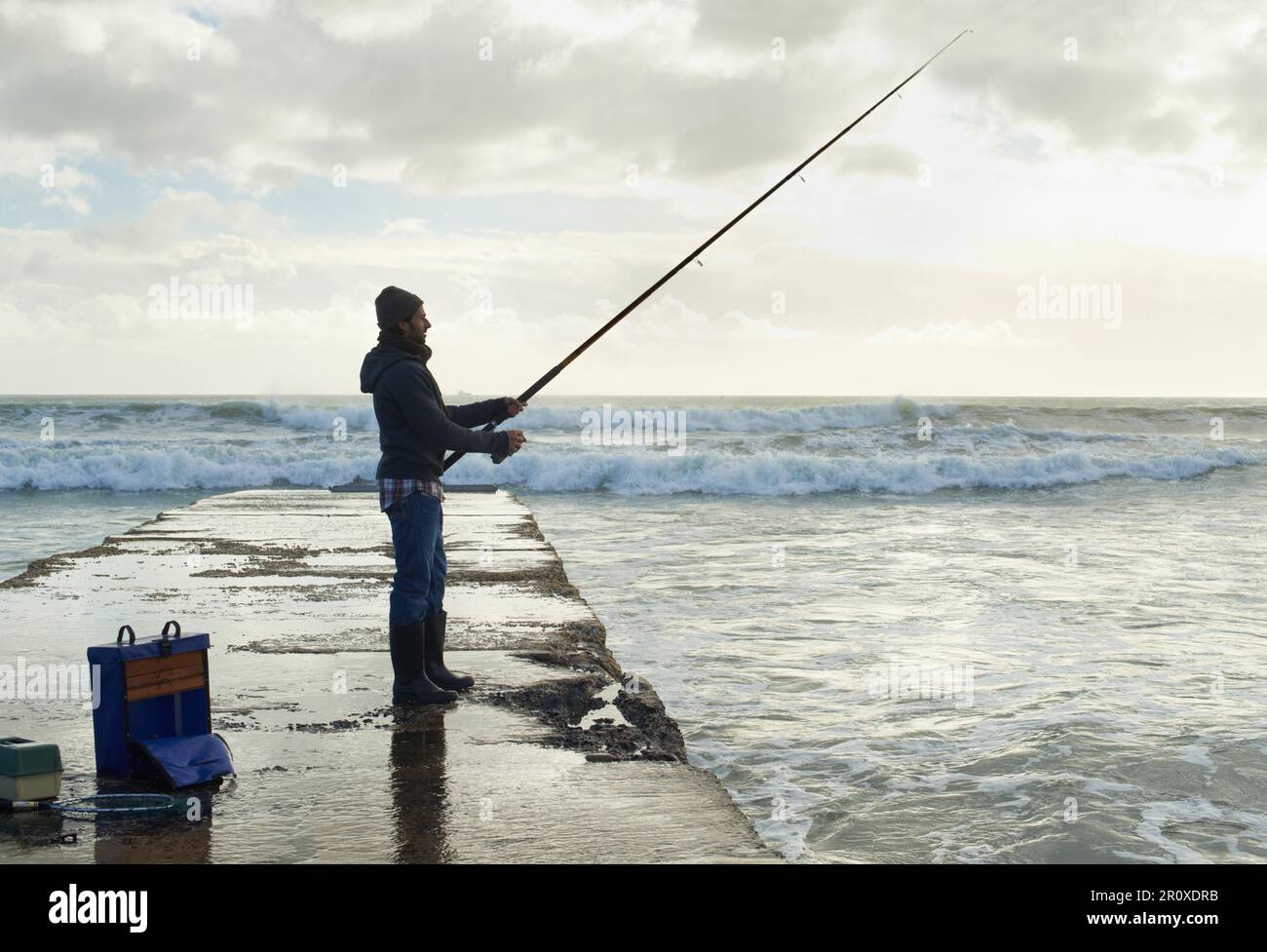 Taking his time for the big catch. a solo fisherman fishing off a pier ...