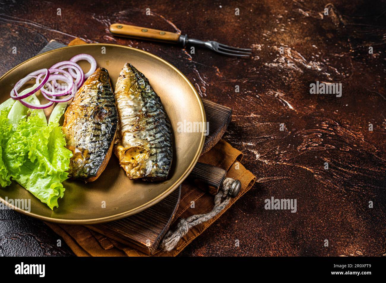Grilled mackerel scomber fish fillets with garnish in a plate. Dark ...
