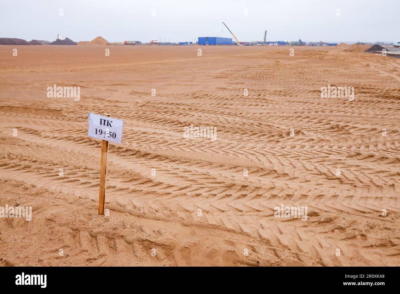 Flat sand subgrade, sign and truck trails. Blue sky on horizon Stock ...