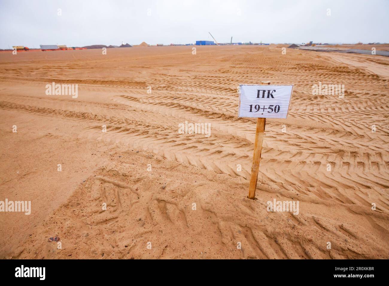 Flat sand subgrade, sign and truck trails. Blue sky on horizon Stock ...