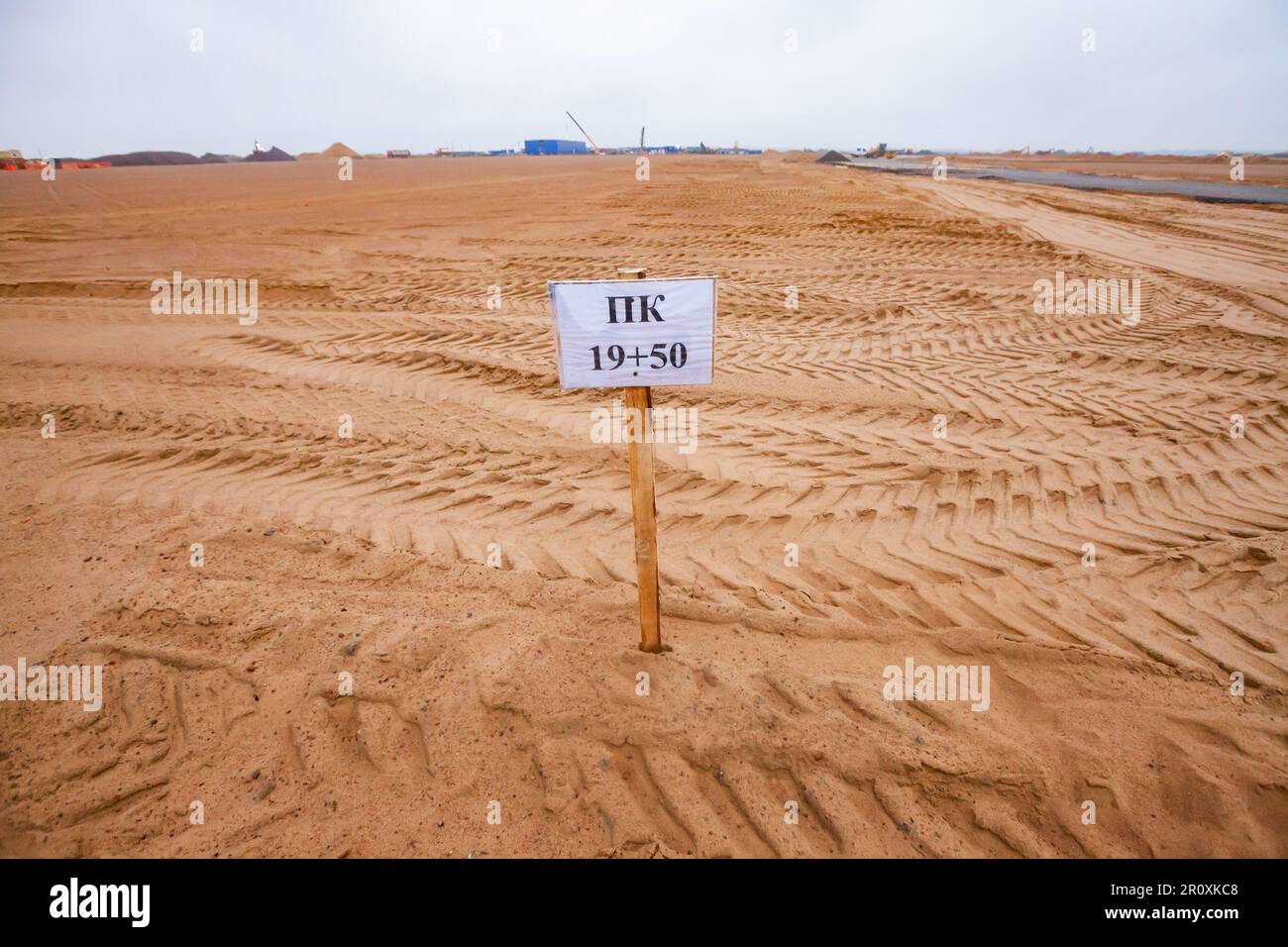 Flat sand subgrade, sign and truck trails. Blue sky on horizon Stock ...