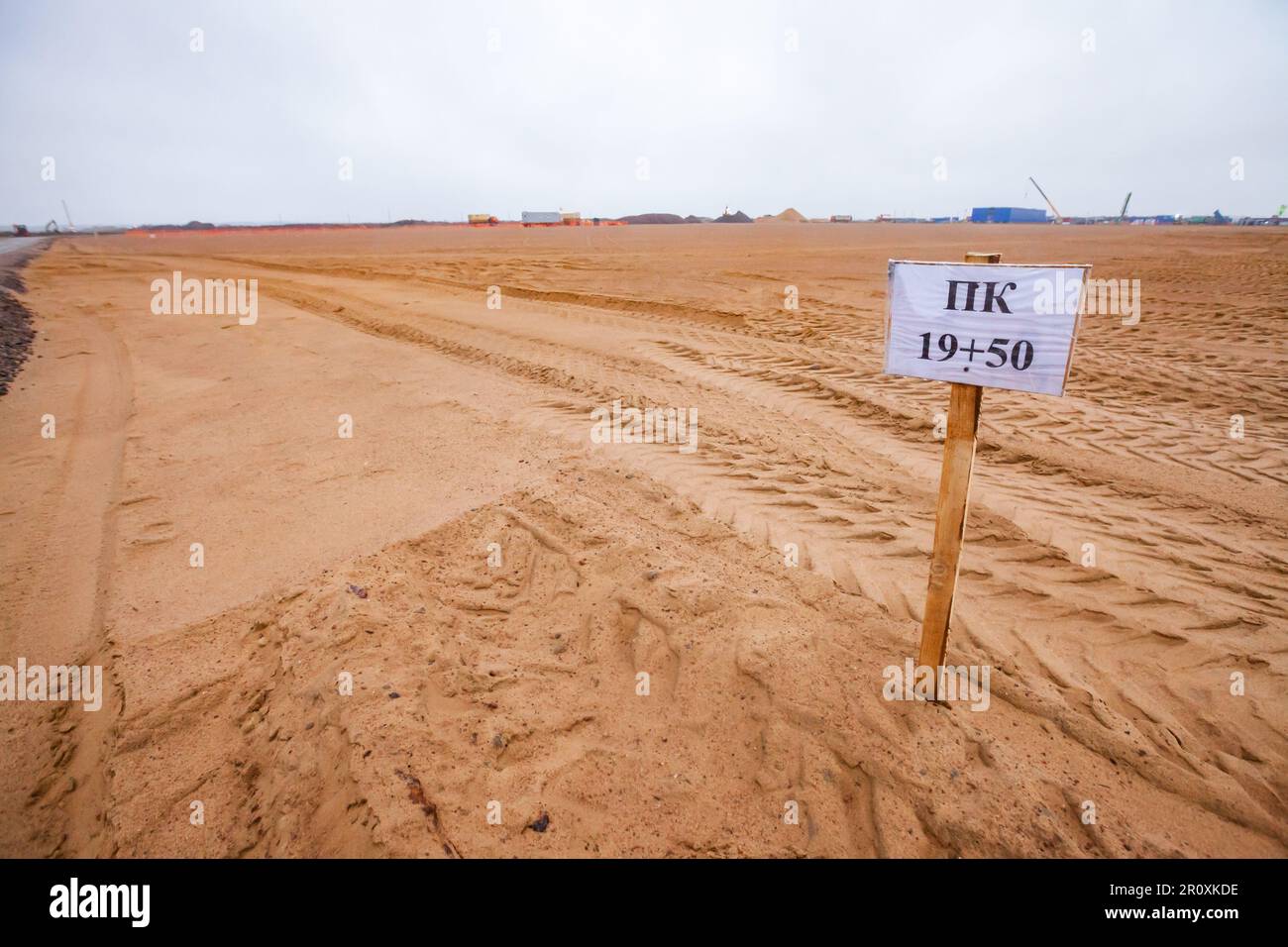 Flat sand subgrade, sign and truck trails. Blue sky on horizon Stock ...