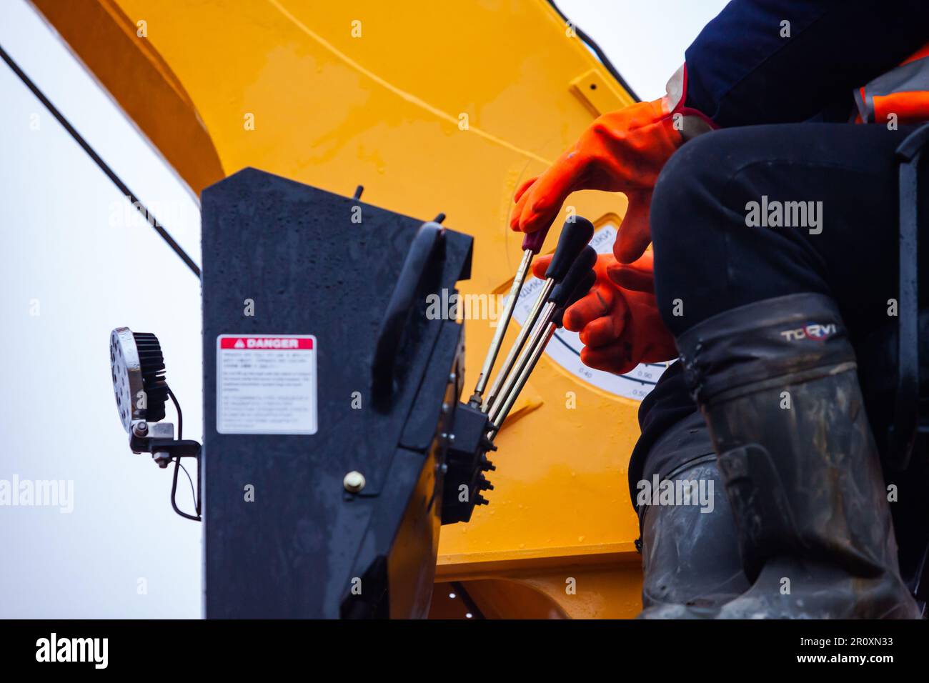 Mobile crane control levers and operator's hands in orange rubber ...