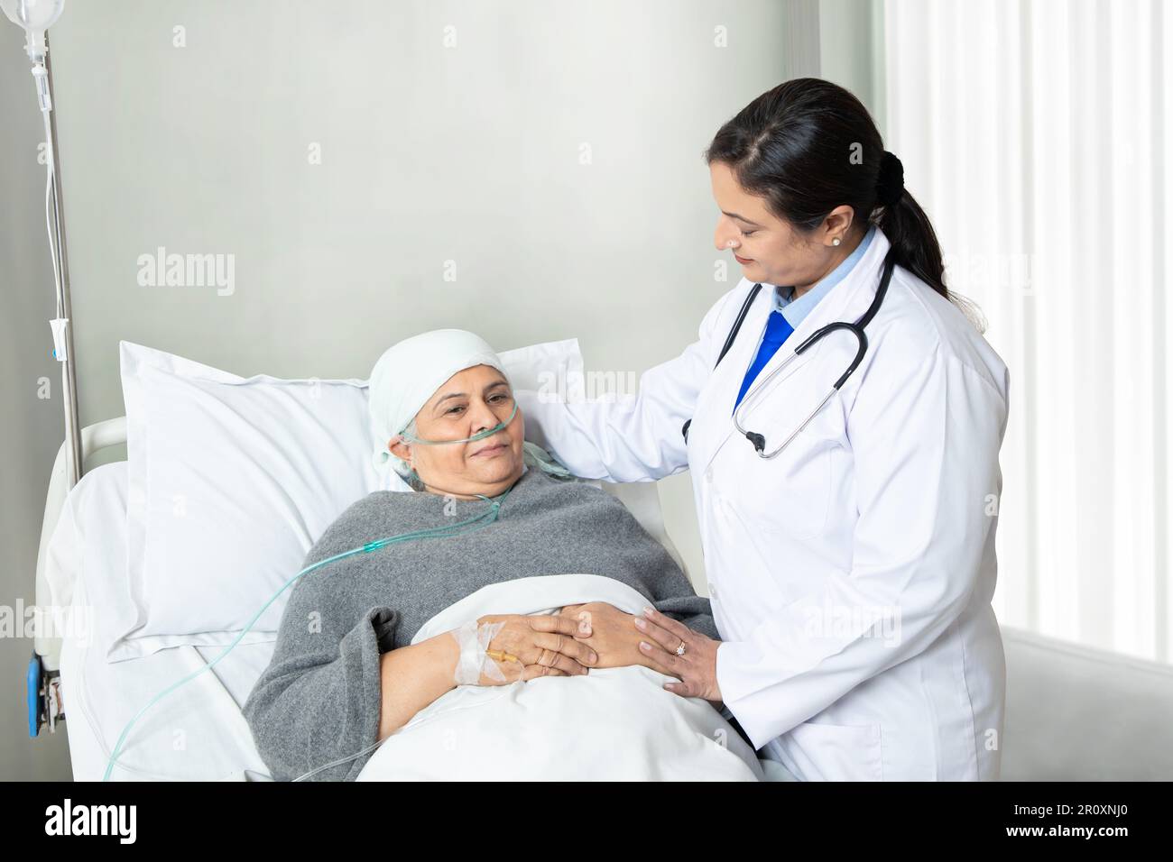 Indian doctor visit senior patient with nasal cannula lying in hospital ...