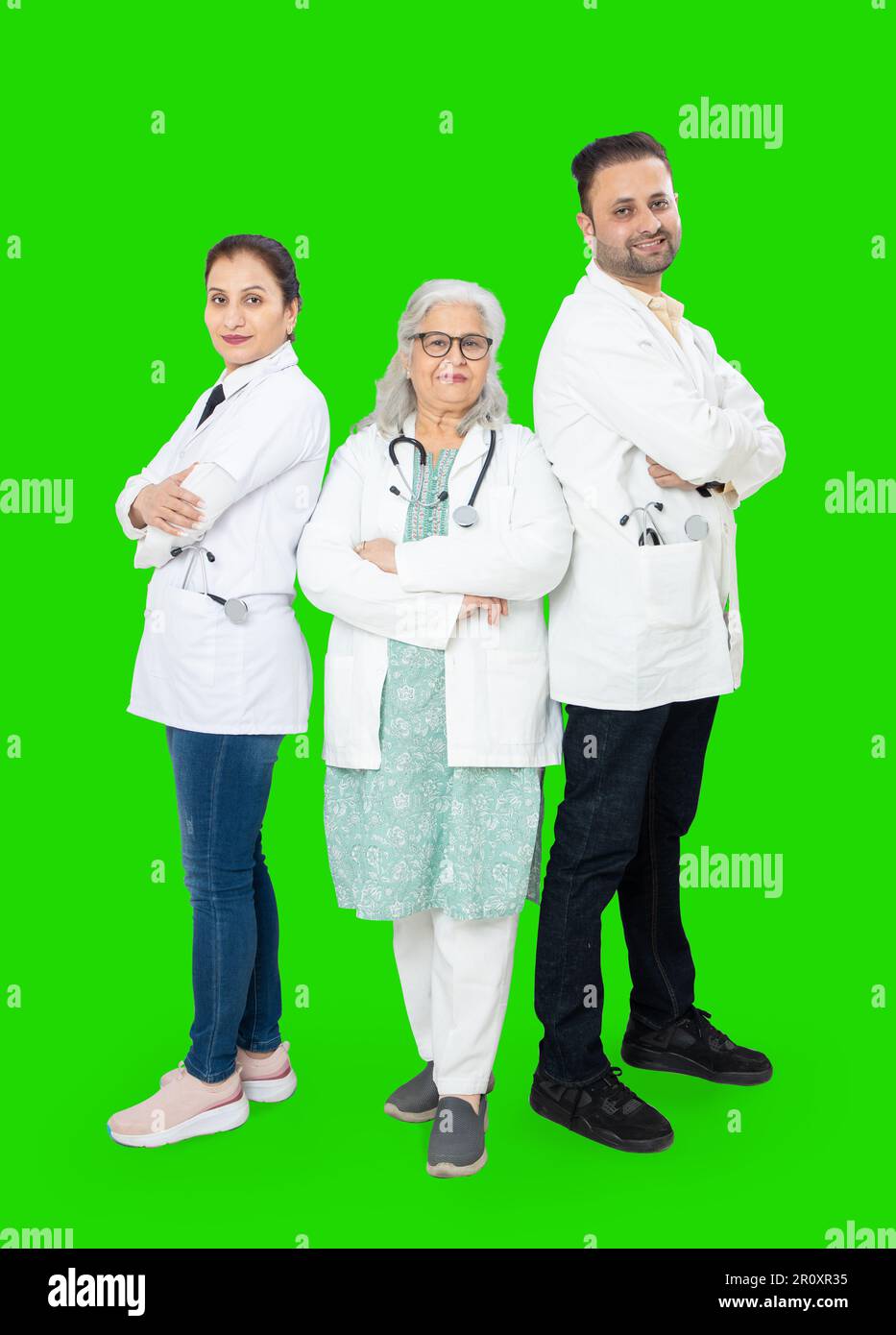 Team of indian doctors standing standing cross arms isolated over green studio background ...
