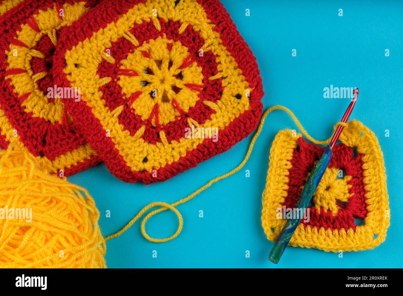 Granny square in yellow and red being crocheted, with two granny ...