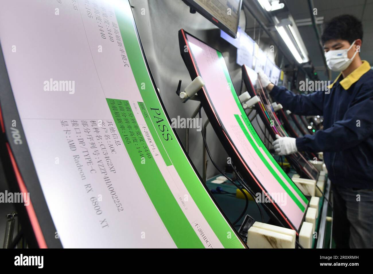 A worker checks the curvy screens under production at a subsidiary of ...
