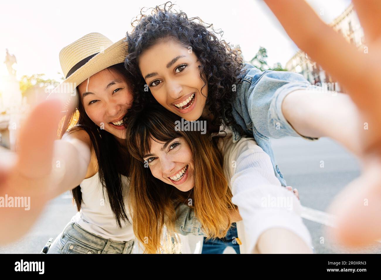 Three multiracial young women having fun on city street Stock Photo - Alamy