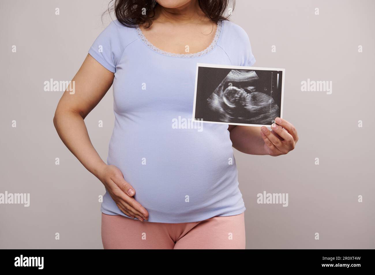 Cropped view pregnant woman caressing her belly, showing at camera the ...