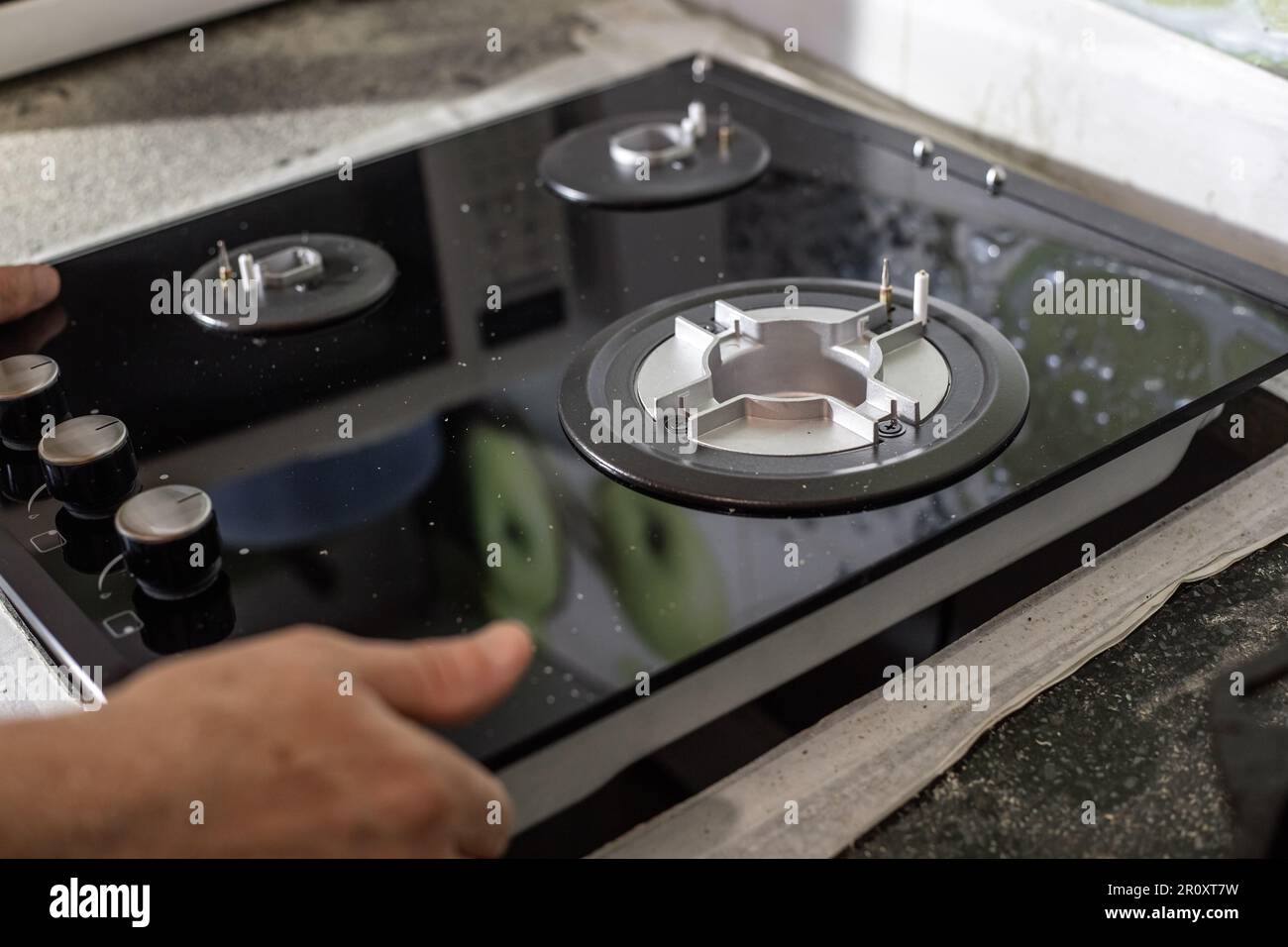 A man installs a built-in glass-ceramic gas stove on a kitchen ...