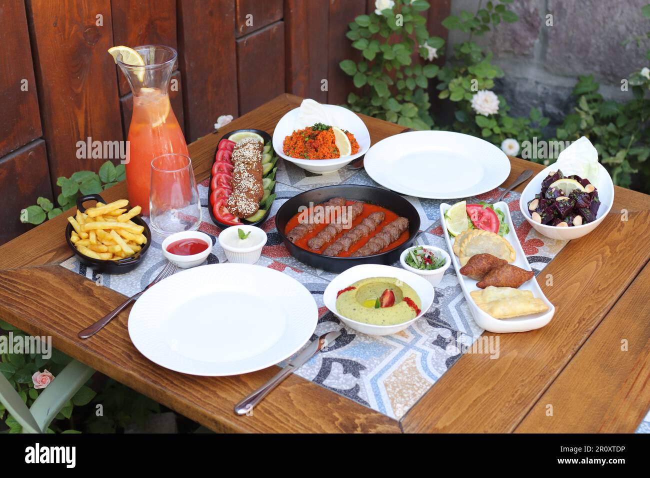 A wooden table with different types of food like kabab, french fries ...