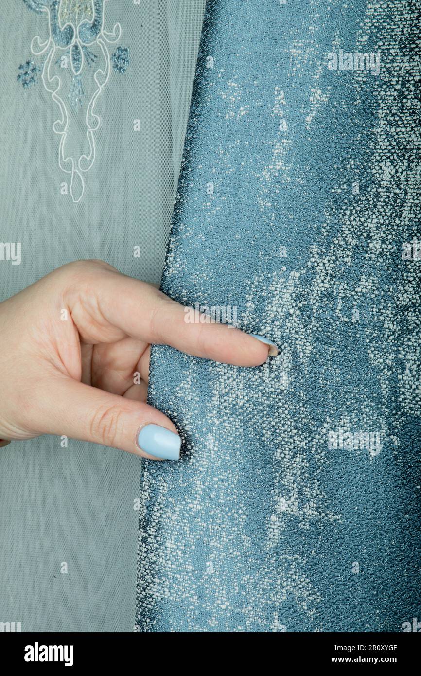 A close-up of a female hand adjusting a piece of blue fabric Stock ...