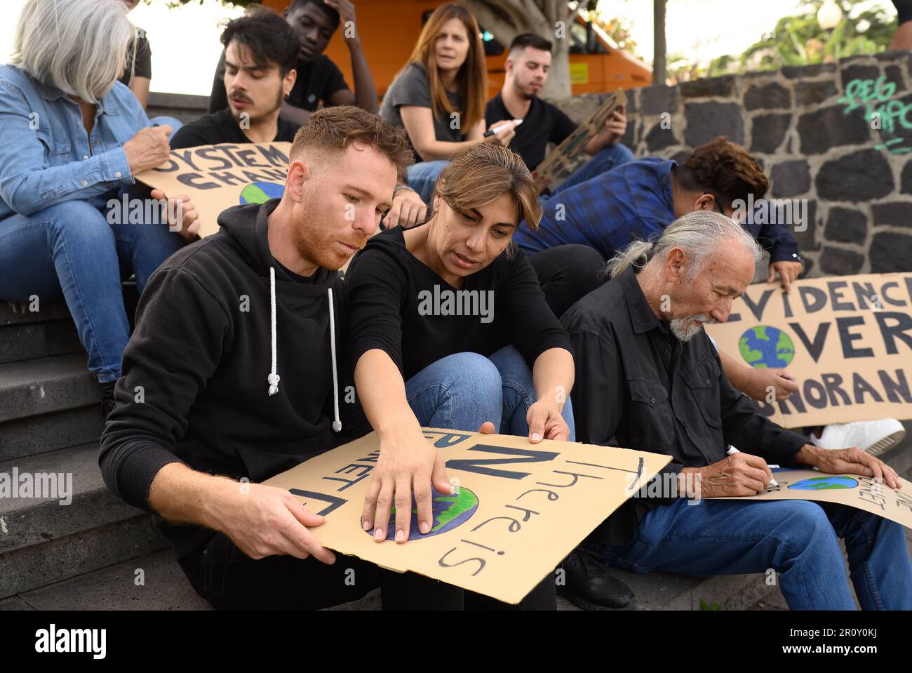 Group of focused diverse protesters creating carton placards while ...