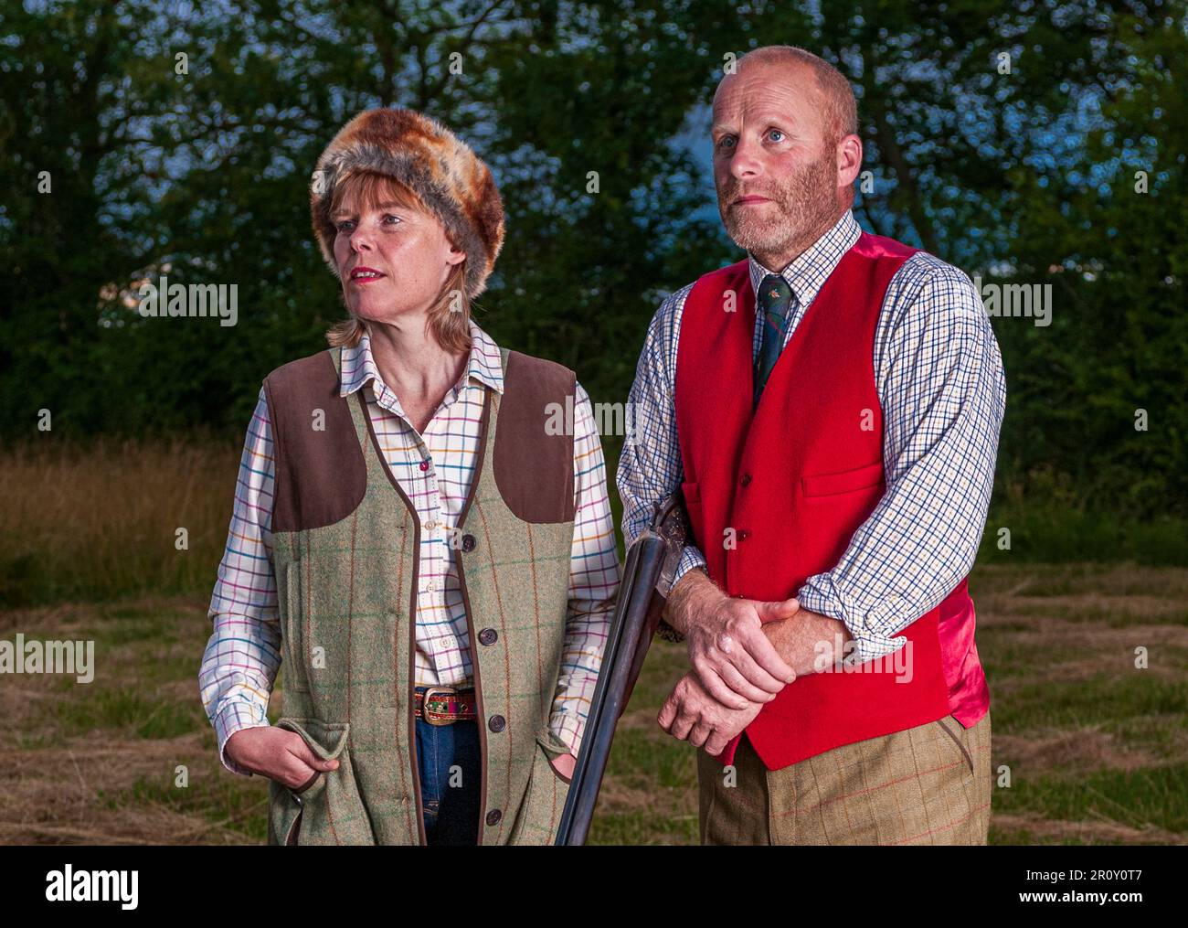 An English lady and gentleman stood at twilight in shooting suits with ...