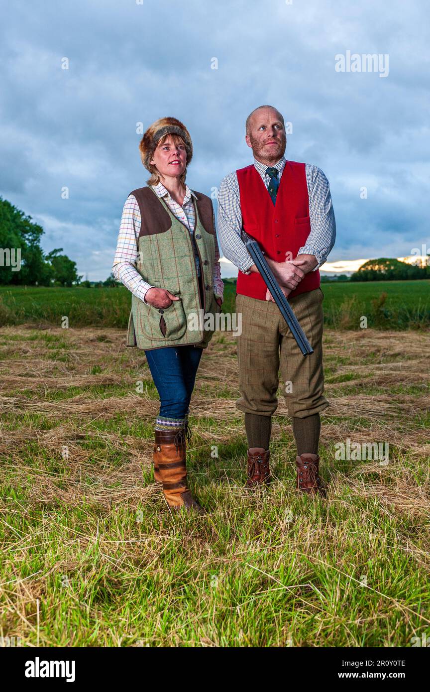 An English lady and gentleman stood at twilight in shooting suits with ...
