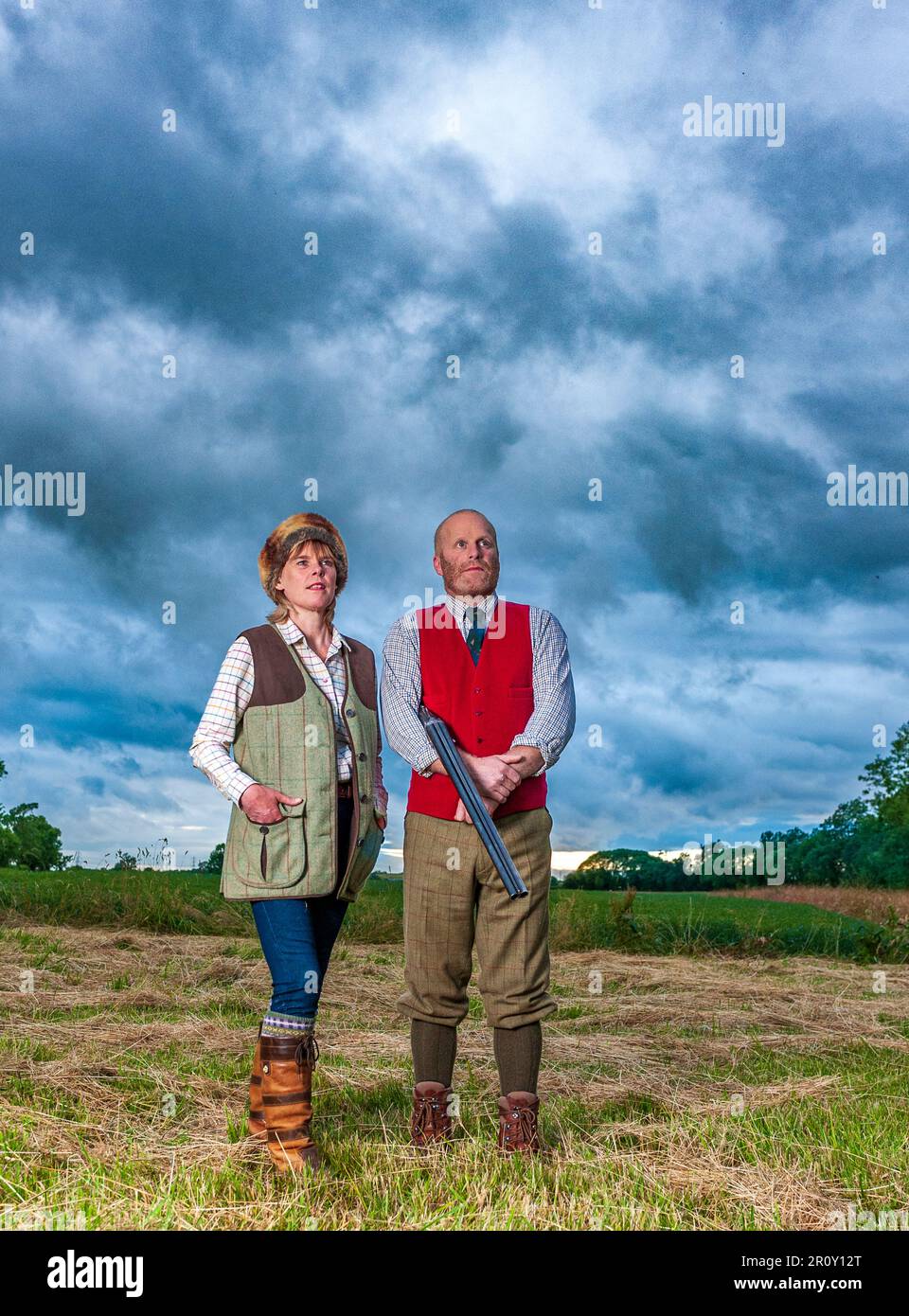 An English lady and gentleman stood at twilight in shooting suits with ...