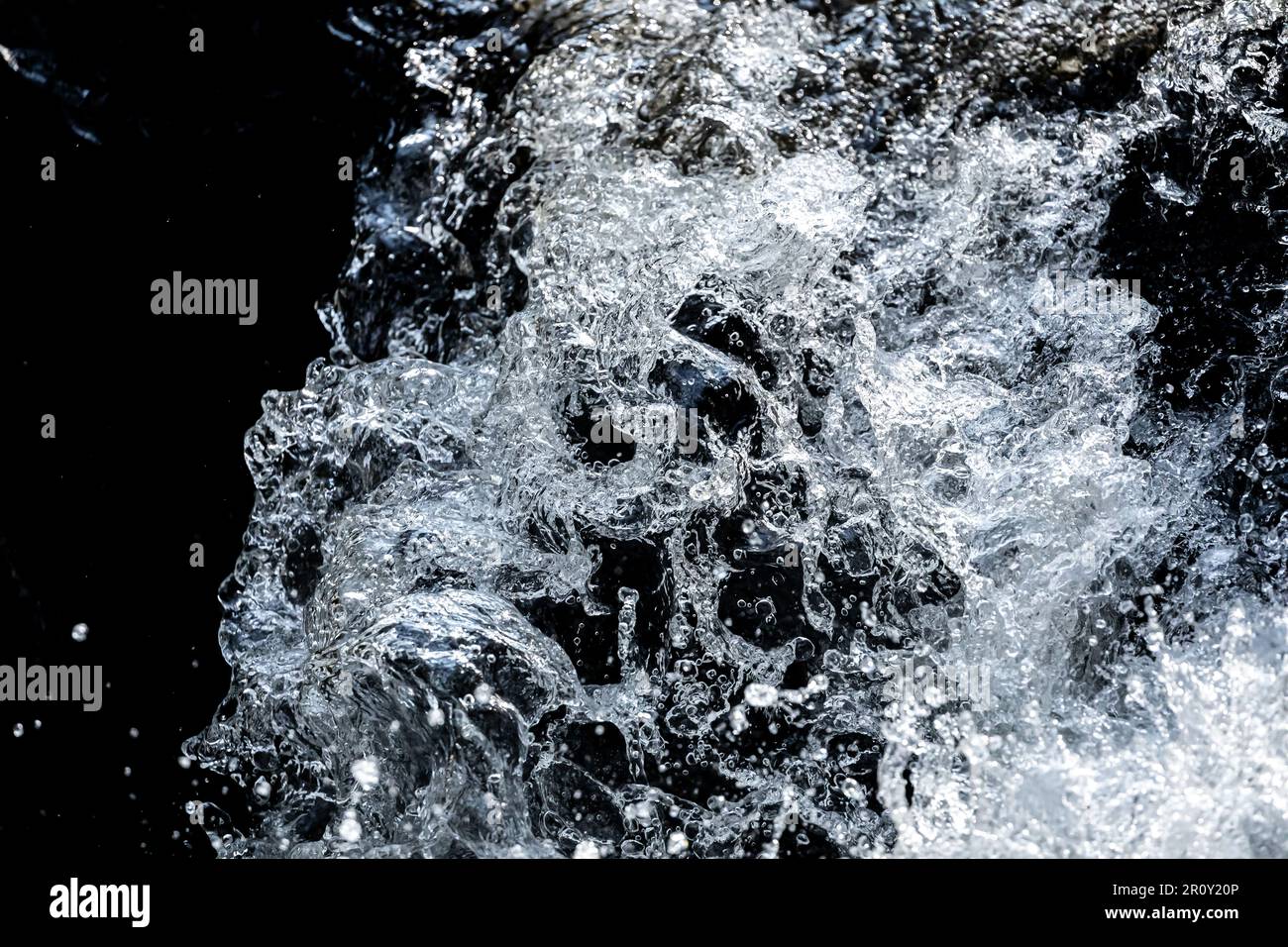 Close focus on fast moving water in river with stopped motion technique ...