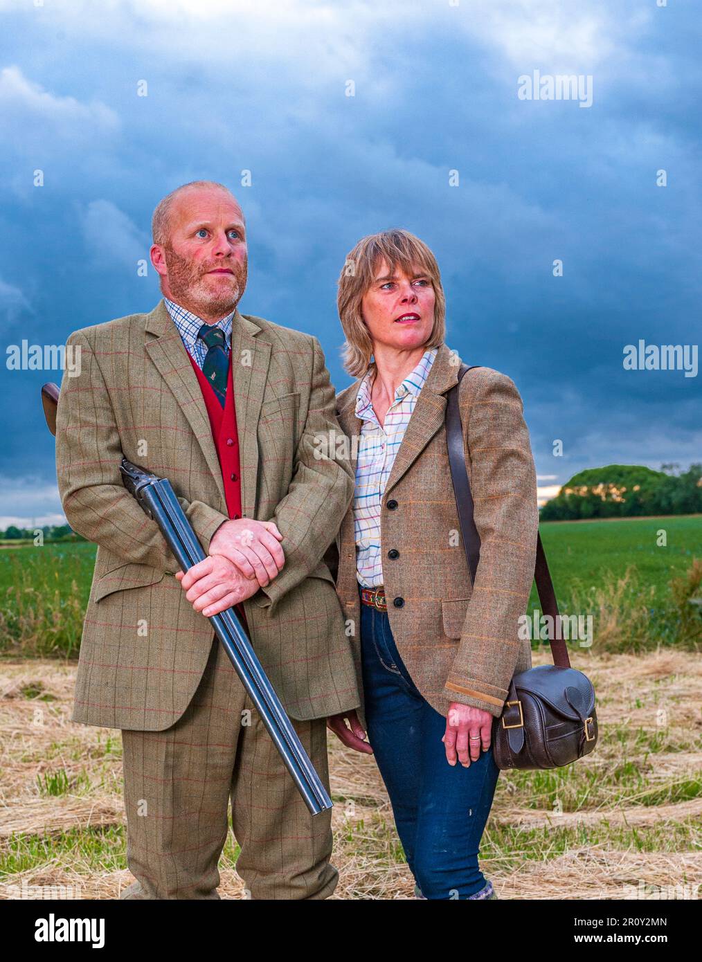 An English lady and gentleman stood at twilight in shooting suits with ...