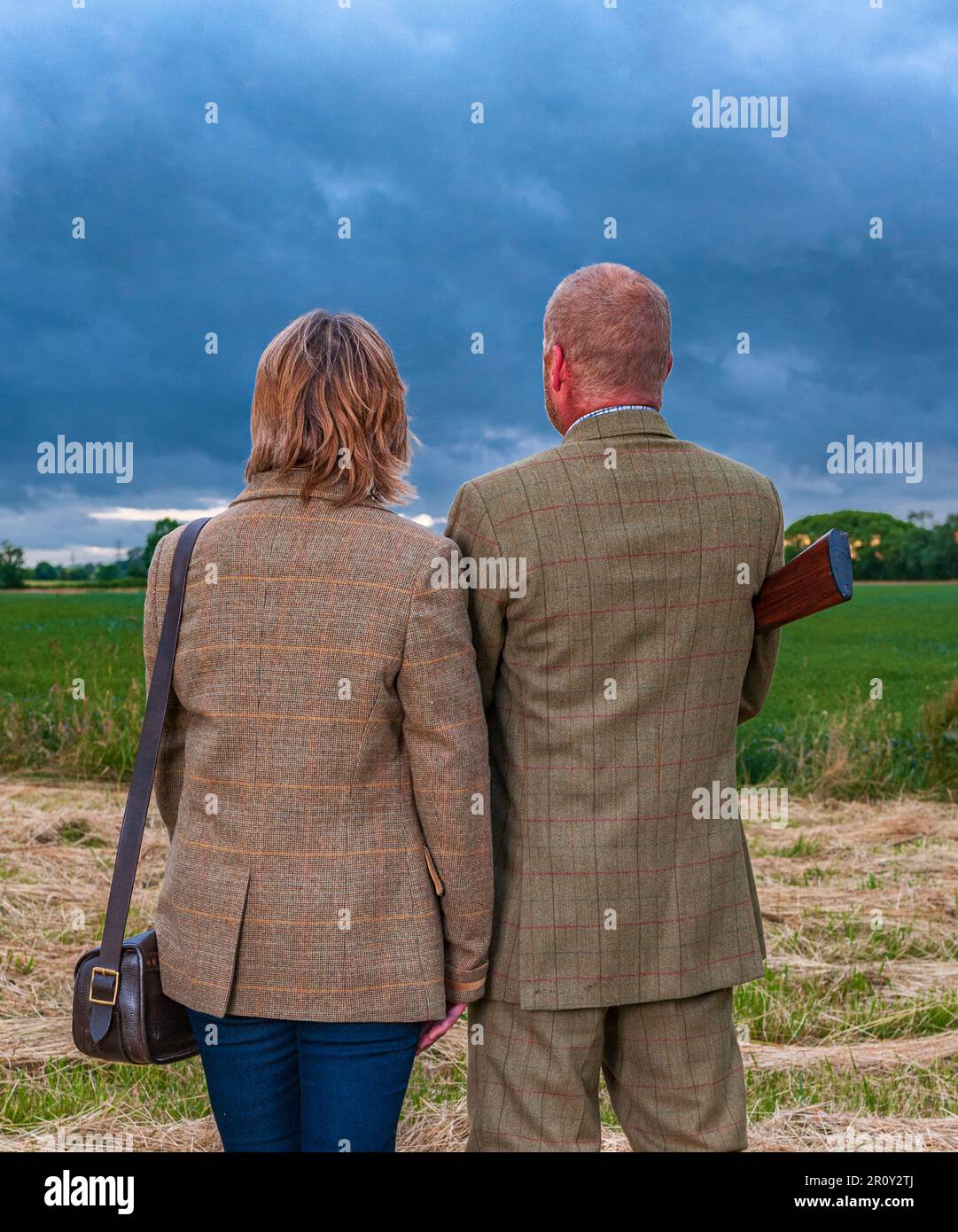 An English lady and gentleman stood at twilight in shooting suits with ...