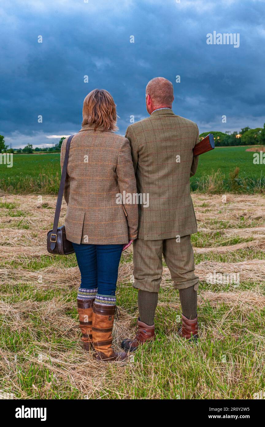 An English lady and gentleman stood at twilight in shooting suits with ...
