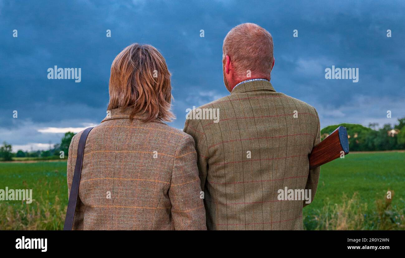 An English lady and gentleman stood at twilight in shooting suits with ...