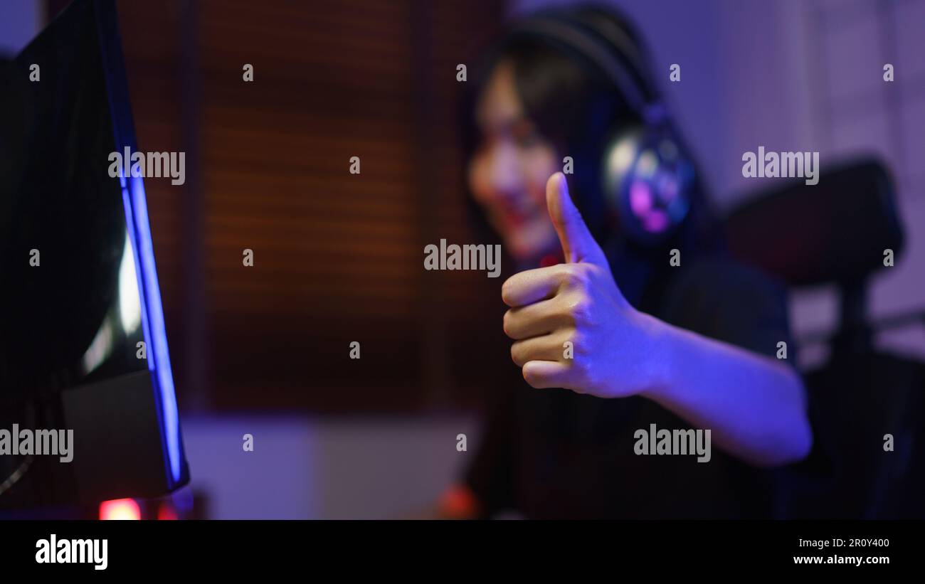 Female cyber hacker gamer in headphone showing thumb up after hacking ...