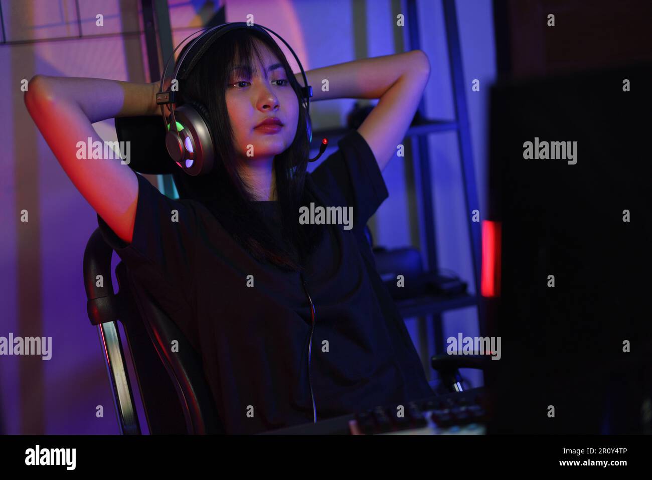 Female cyber hacker gamer holds hands behind head to resting after ...