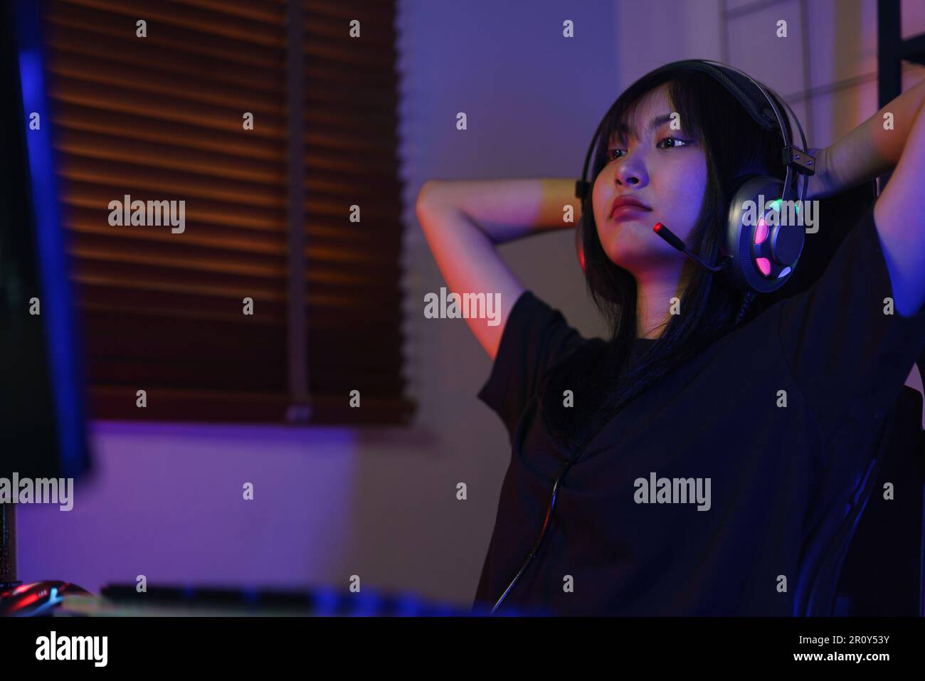 Female cyber hacker gamer holds hands behind head to resting after ...