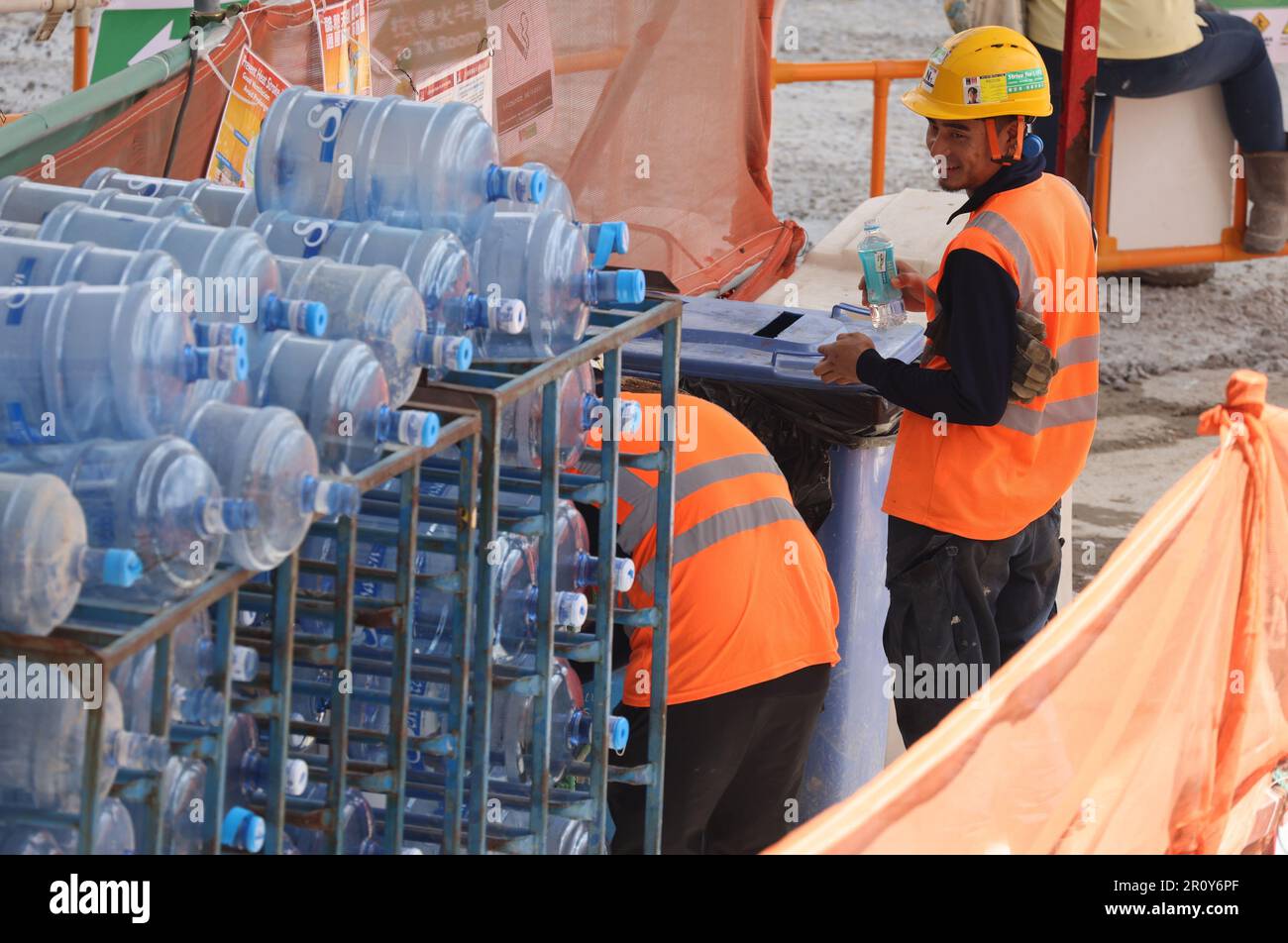 Construction workers stand in the heat under hot weather at a ...
