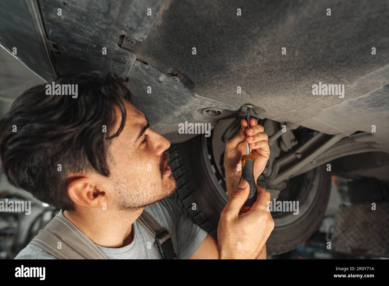 Workman mechanic working under car in auto repair shop Stock Photo - Alamy