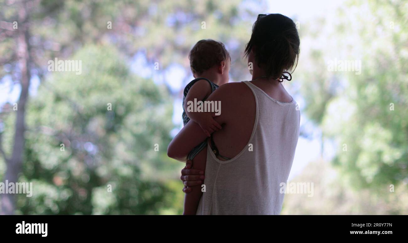 Candid mother holding baby outside in home garden Stock Photo - Alamy