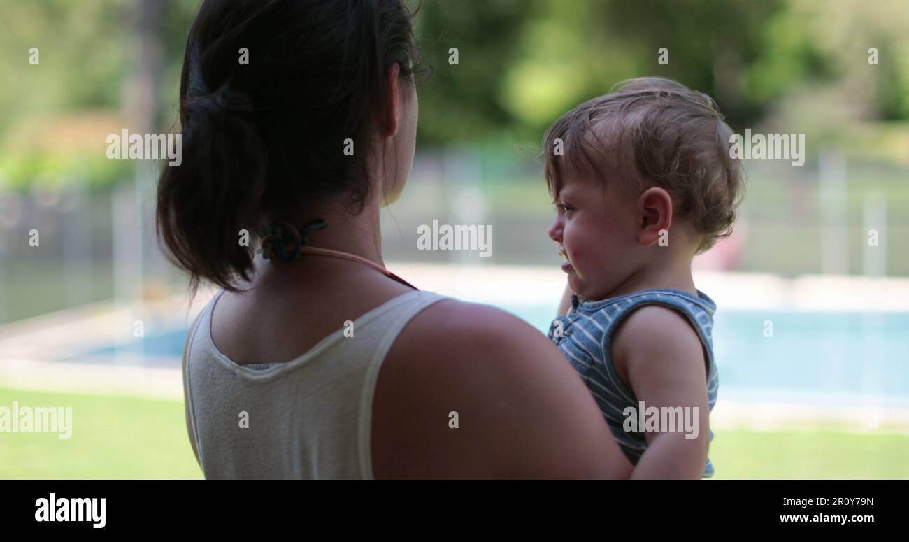 Candid mother holding baby outside, mom calming and consoling infant ...
