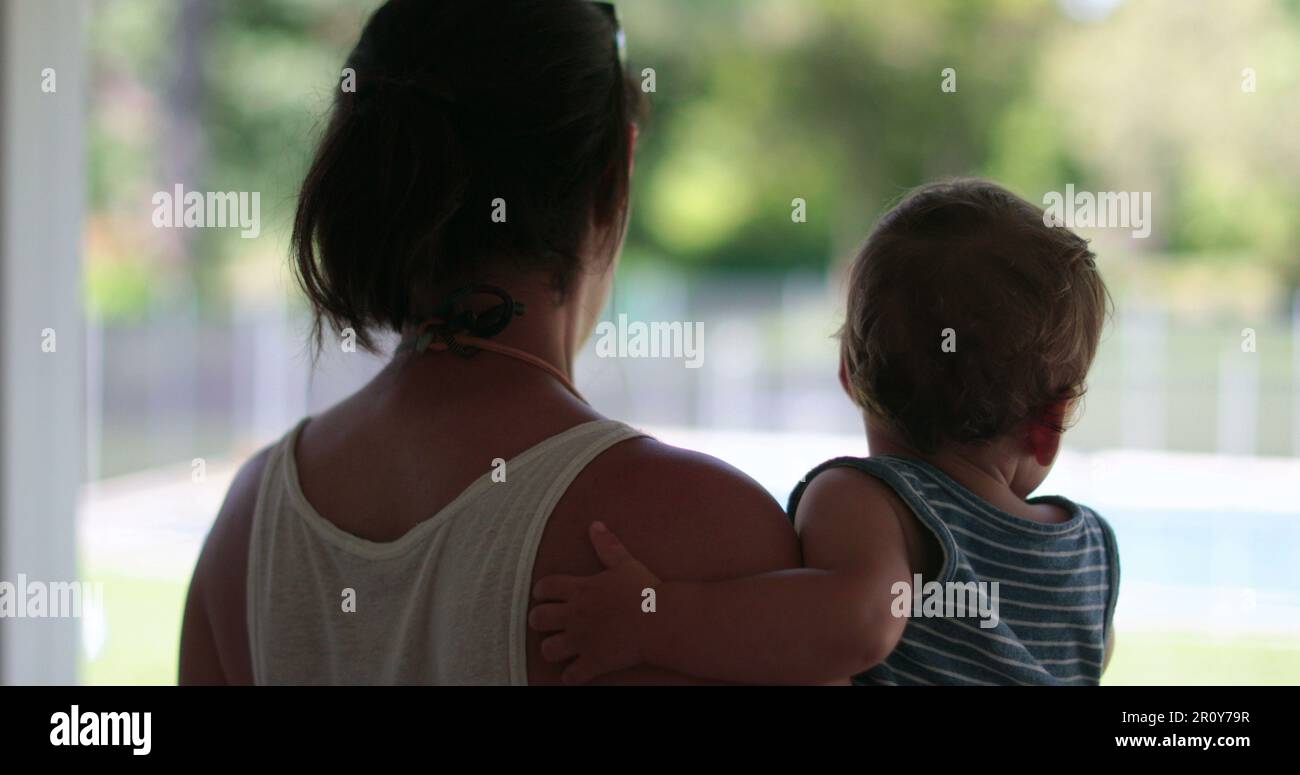 Candid mother holding baby outside, mom calming and consoling infant ...