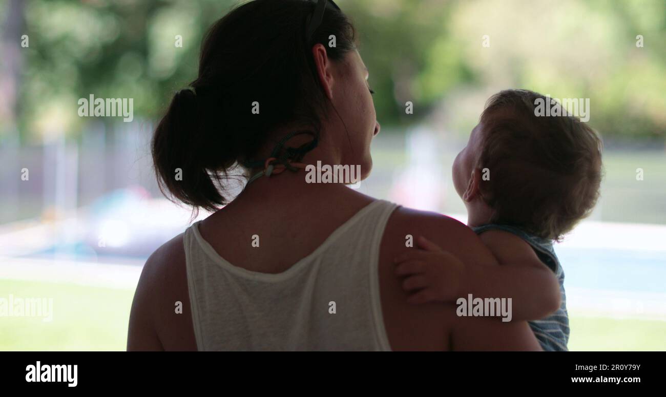 Candid mother holding baby outside, mom calming and consoling infant ...