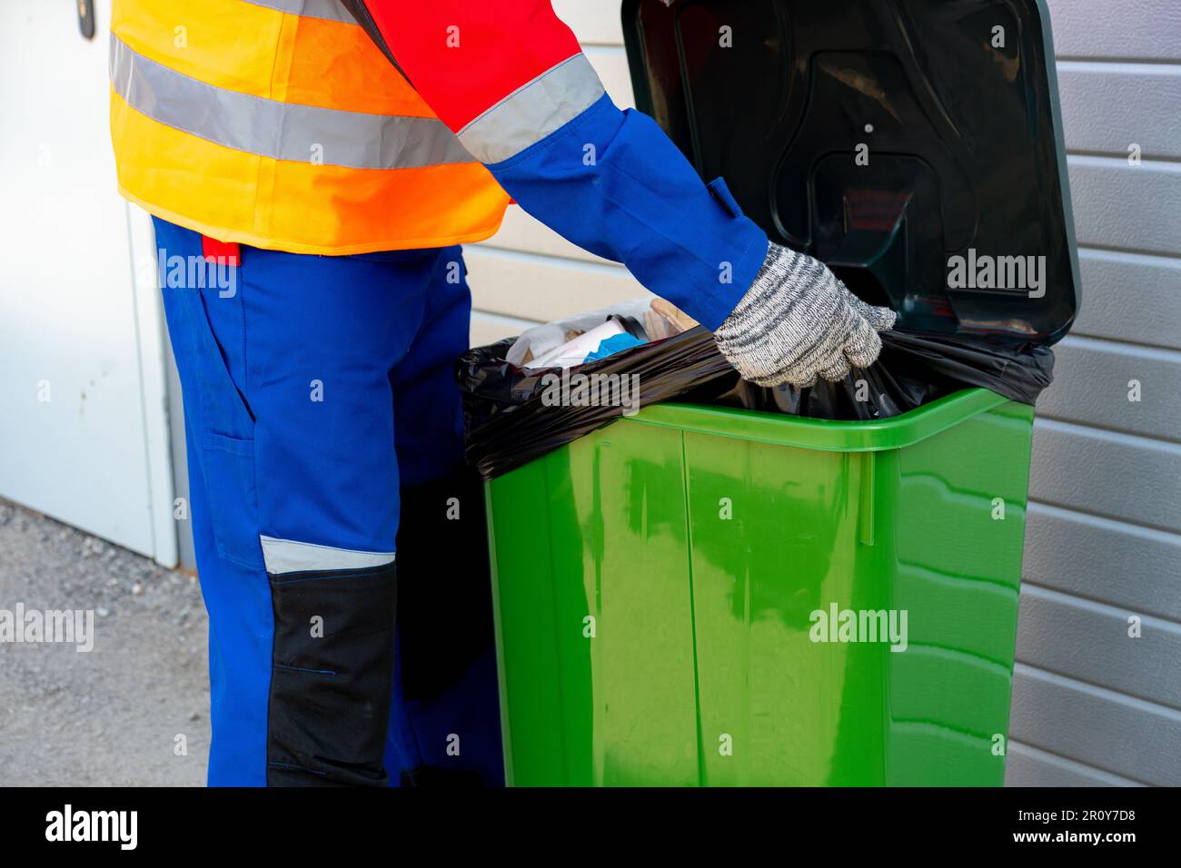 Janitor takes garbage out of trash container outdoors Stock Photo - Alamy