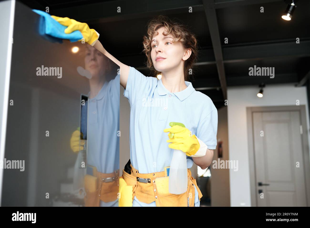 Professional cleaner wiping dust in the room using detergent and rag ...