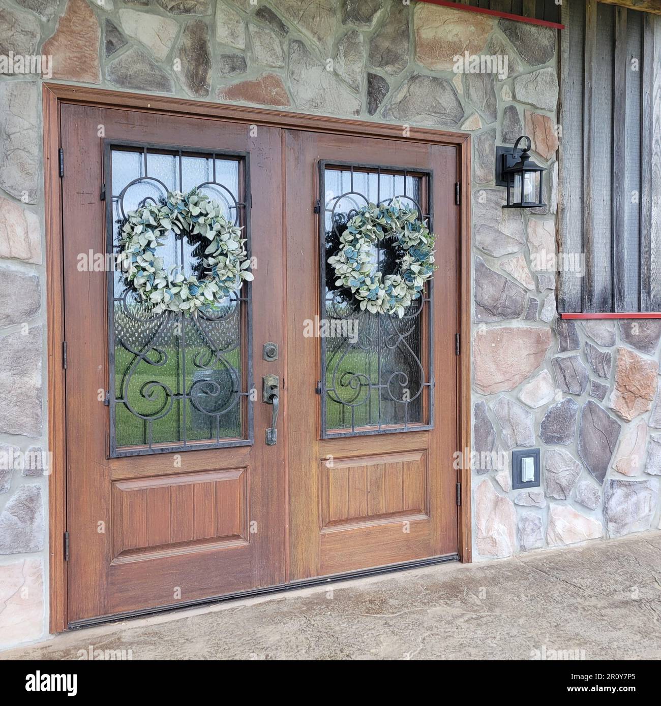 Fancy wooden doors mark the entrance into a stone and wood barn built ...