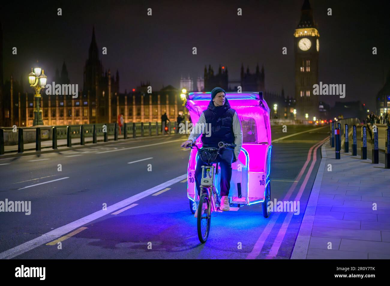 LONDON - April 21, 2023: A vibrant pink and blue rickshaw is parked on ...