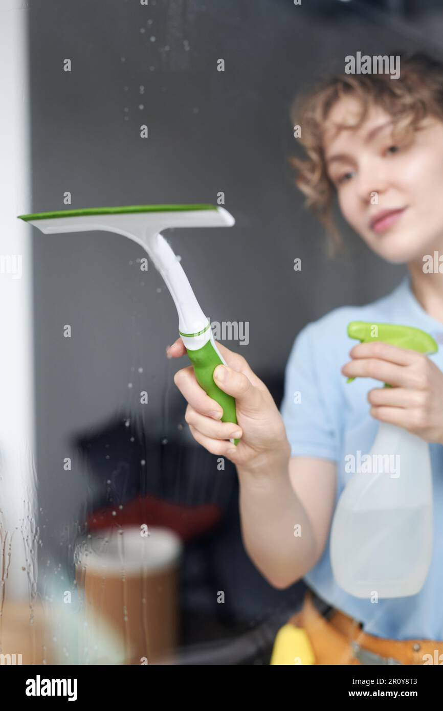 Vertical image of young professional worker cleaning the window with ...