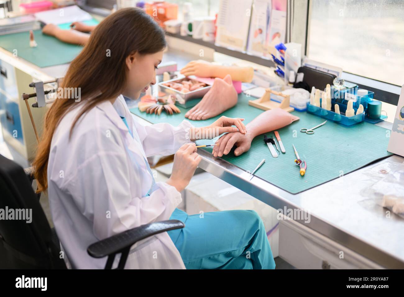 Technician making prosthetic device using grinder to smooth socket ...